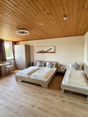 Quarto com duas camas, uma escrivaninha e uma cadeira.