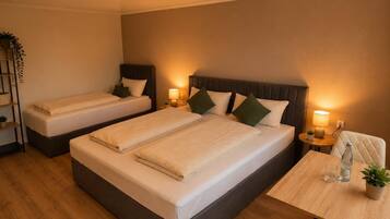 Quarto de hotel com uma cama grande, duas camas menores, uma mesa de cabeceira, uma cadeira e um lustre.