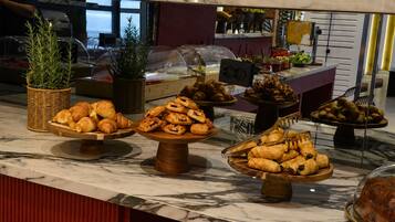 Balcão de buffet com diversos produtos de panificação e uma planta decorativa.