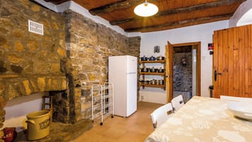Uma cozinha rústica com paredes de pedra, geladeira branca e teto de madeira.