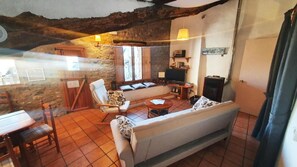 Uma sala de estar acolhedora com sofá, poltronas, mesa de centro e televisão.