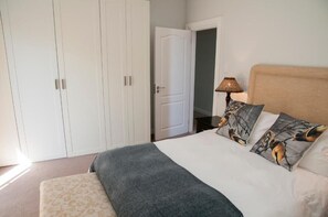 Quarto com cama, abajur e guarda-roupa.