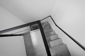 Uma escadaria moderna com corrimão de metal e parede de concreto.