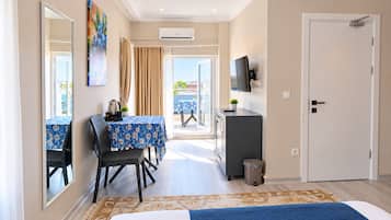 Quarto de hotel com área de refeições, TV fixada na parede e porta para uma varanda.