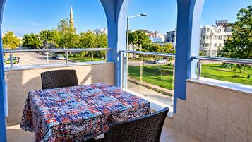 Uma varanda com mesa e cadeiras, vista para uma mesquita e um prédio com uma placa.