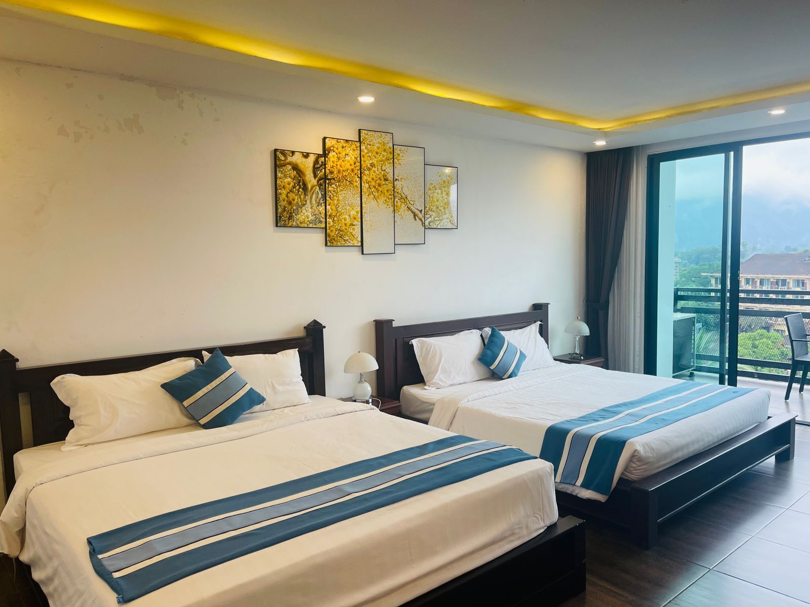 Quarto de hotel com duas camas, uma janela grande e vista para a cidade.