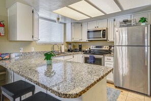 Cozinha com bancadas de granito, eletrodomésticos de aço inoxidável e armários brancos.