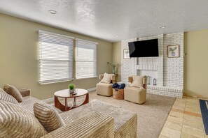 Uma sala de estar com lareira, dois sofás, uma mesa de centro e uma televisão de tela plana na parede.