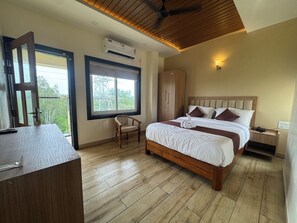 Quarto de hotel com cama, cadeira, guarda-roupa e escrivaninha.