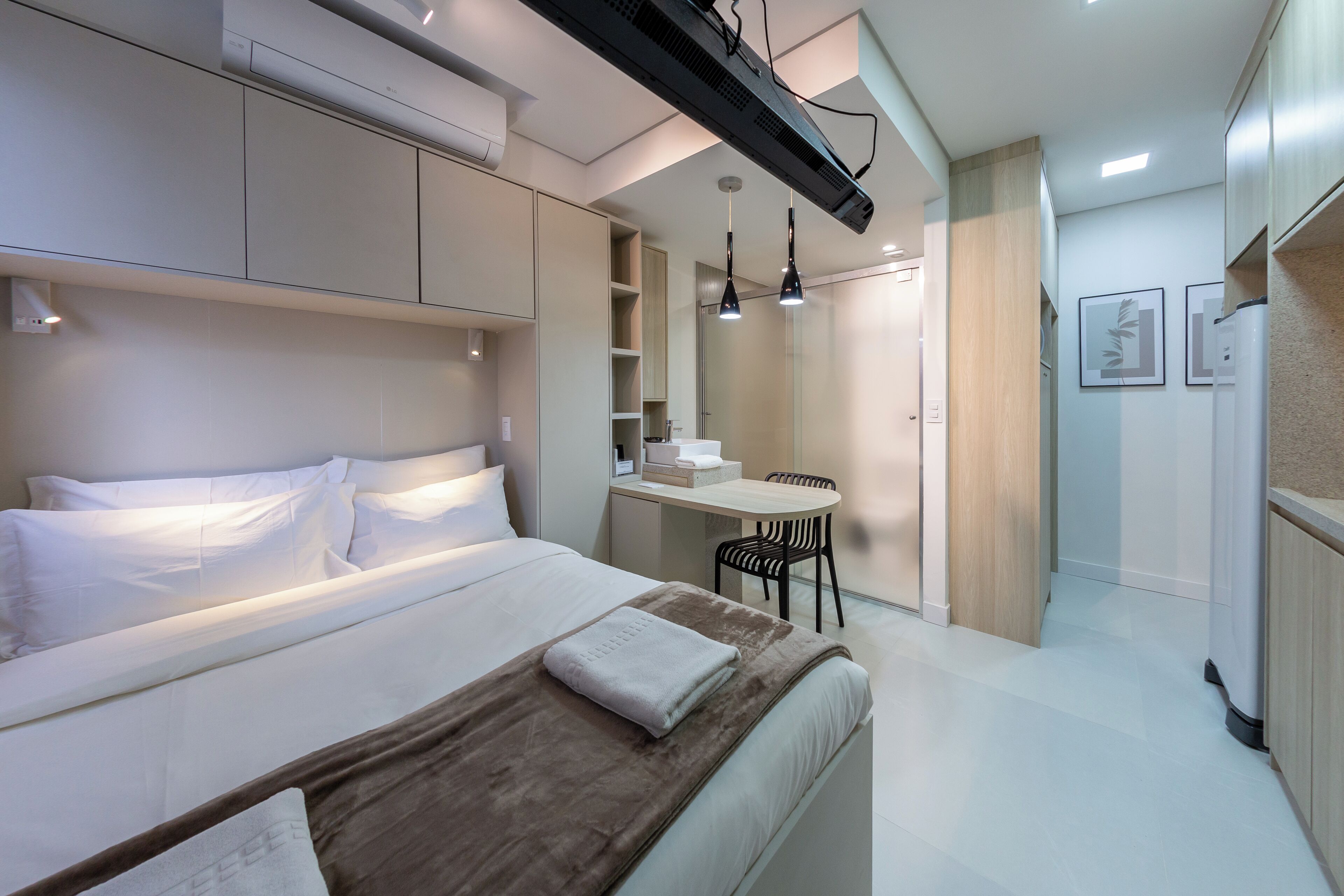 Quarto moderno com cama, mesas de cabeceira, escrivaninha e cadeira.