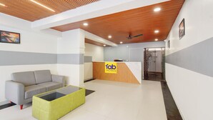 Uma área de recepção de hotel com balcão, sofá e mesa de centro.