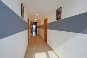 Um corredor com piso ladrilhado, paredes brancas e portas em ambos os lados.