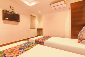 Quarto de hotel com duas camas, televisão, ar condicionado e um relógio na parede.
