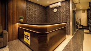 Uma receção de hotel com acabamento em madeira, um relógio e uma unidade de ar condicionado acima.