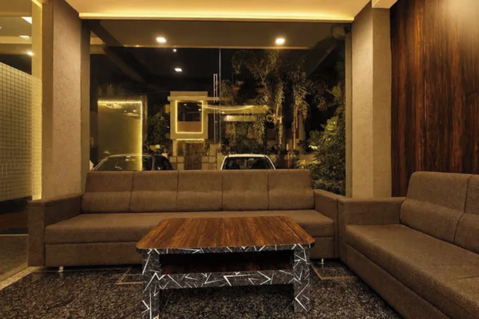 Um interior moderno com sofá seccional, mesa de centro de madeira e vista para o horizonte urbano através de uma grande janela.
