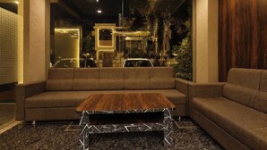 Um interior moderno com sofá seccional, mesa de centro de madeira e vista para o horizonte urbano através de uma grande janela.