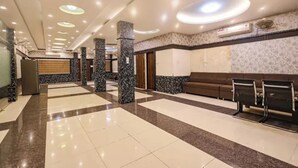 Um hall amplo com piso de mármore, balcão de recepção e área de estar com cadeiras.