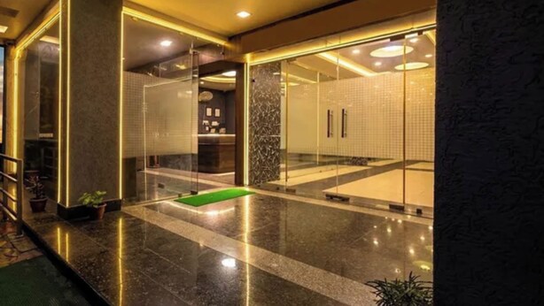 Um saguão de hotel com divisória de vidro, balcão de recepção e carpete verde.