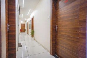 Um corredor com portas de madeira, paredes brancas e chão de azulejos.