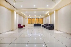 Um hall amplo com teto alto, iluminação embutida e área de estar com sofás e cadeiras.