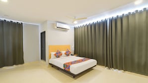 Quarto de hotel com cama, cortinas, ar condicionado e ventoinha de teto.