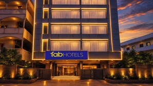 Um hotel com vários andares, fachada moderna, grandes janelas e um letreiro chamativo 'fab hotels'.