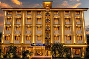 Um hotel de vários andares com fachada simétrica, diversas varandas e uma entrada imponente com degraus.
