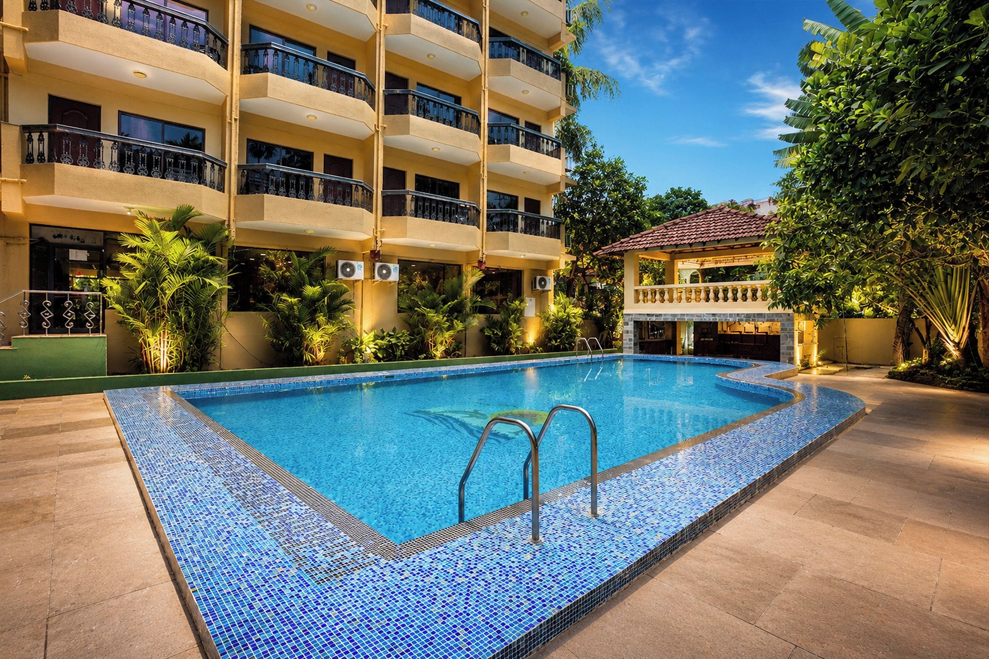 Um hotel com piscina, várias varandas e vegetação exuberante.