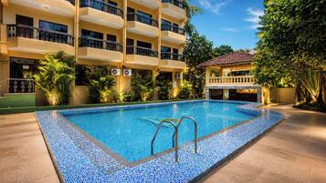 Um hotel com piscina, várias varandas e vegetação exuberante.