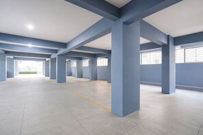 Amplo espaço interior com pé-direito alto e colunas estruturais azuis.
