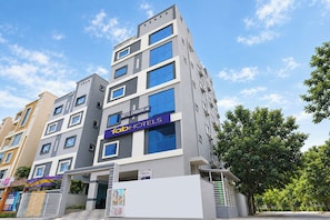 Um edifício de hotel com vários andares e design moderno, exibindo uma placa grande para 'FabHotels' e uma placa para 'Hotel Embark Inn'.
