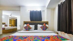 Quarto de hotel com uma cama grande, cabeceira e janela com cortinas.