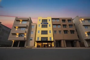Um hotel com vários andares, entrada central, varandas e fachada plana.