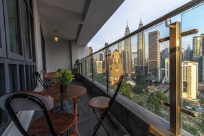Varanda com mesa, cadeiras, um vaso de planta e vista para a cidade.