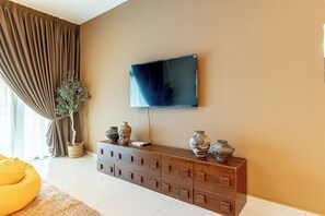 Uma sala de estar moderna com televisão de tela plana na parede, mesa de console de madeira com vasos decorativos, uma planta em vaso e uma poltrona de feijão amarela.