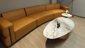 Quarto moderno com sofá curvo, mesa de centro de mármore e abajur.