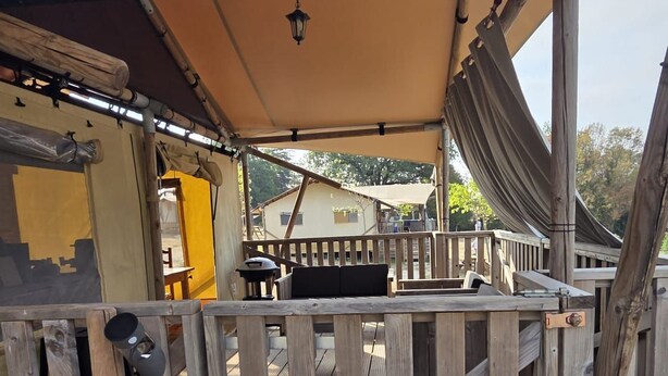 Um deck de madeira com toldo, cercado por uma vedação de madeira.
