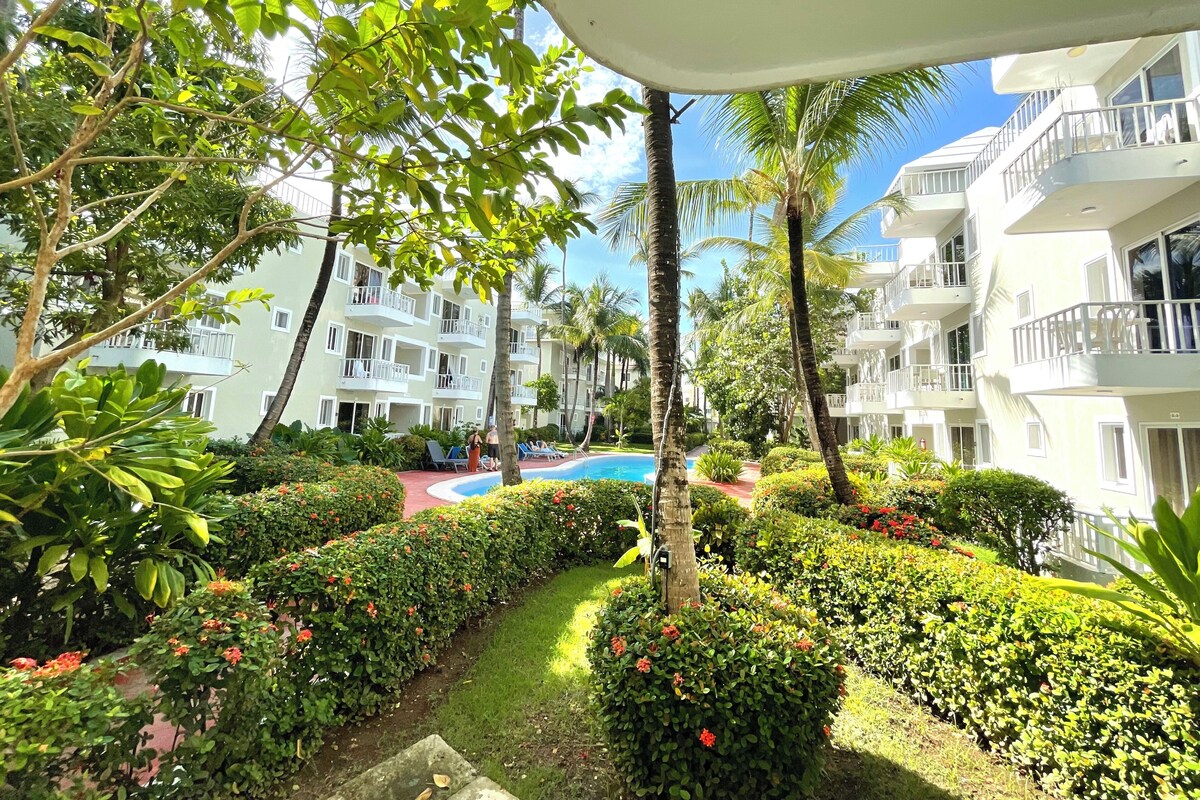 Um hotel com várias varandas, piscina e vegetação exuberante.
