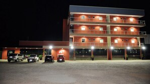 Um hotel com vários andares, teto plano e área de estacionamento na frente.