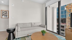 Uma sala de estar moderna com um sofá, uma mesa de centro redonda de madeira e uma planta em vaso.