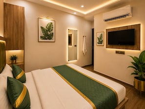 Quarto de hotel com uma cama, televisão, espelho e planta em vaso.