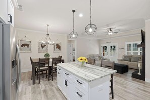 Uma cozinha moderna com ilha de mármore, cadeiras de madeira e luminárias pendentes.