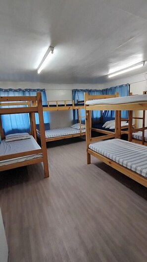 Quarto com beliches, luminária no teto e cortinas.