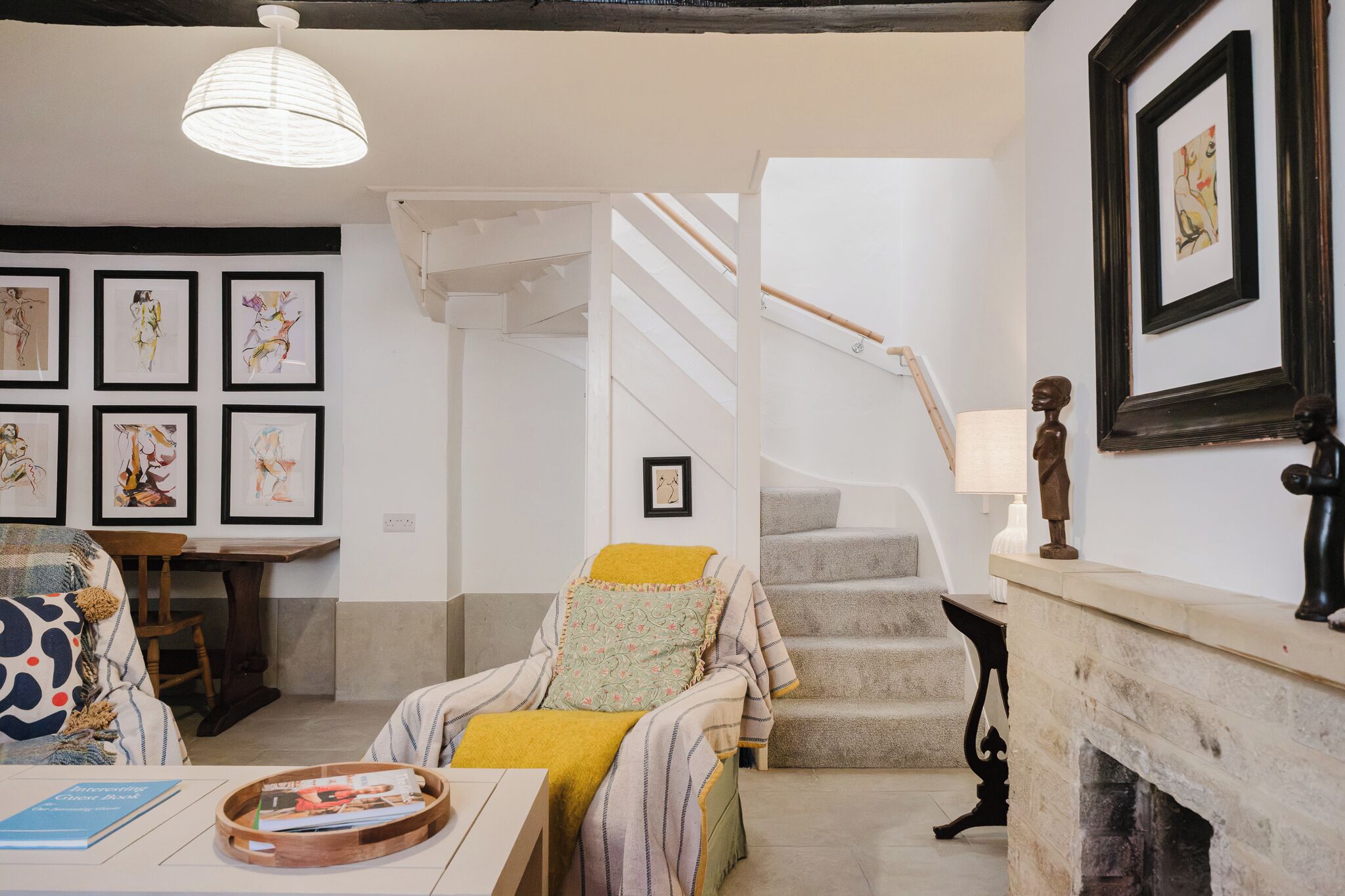 Um quarto com escada, lareira e obras de arte emolduradas nas paredes.