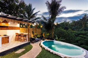 Uma área de piscina ao ar livre com bar e assentos, cercada por vegetação exuberante.