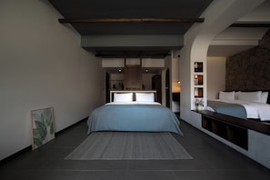 Quarto moderno com uma cama grande, um tapete cinzento e uma parede de pedra.
