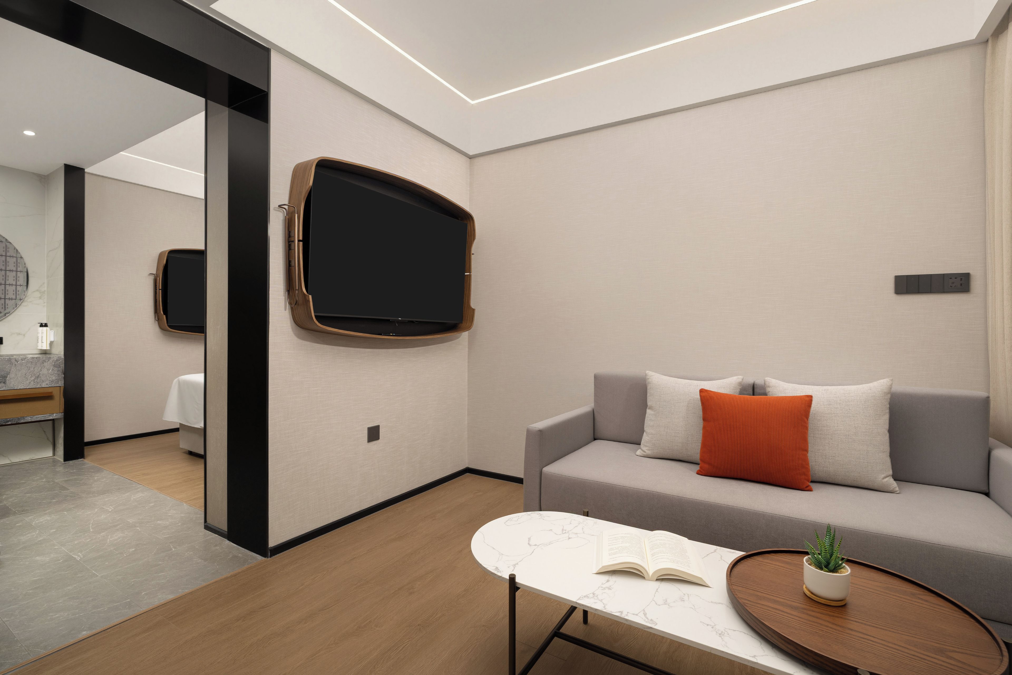 Uma sala de estar moderna com um sofá, uma mesa de centro e uma televisão na parede.