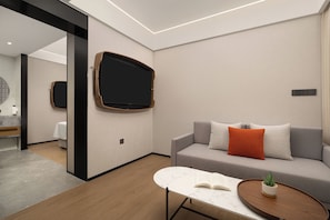 Uma sala de estar moderna com um sofá, uma mesa de centro e uma televisão na parede.