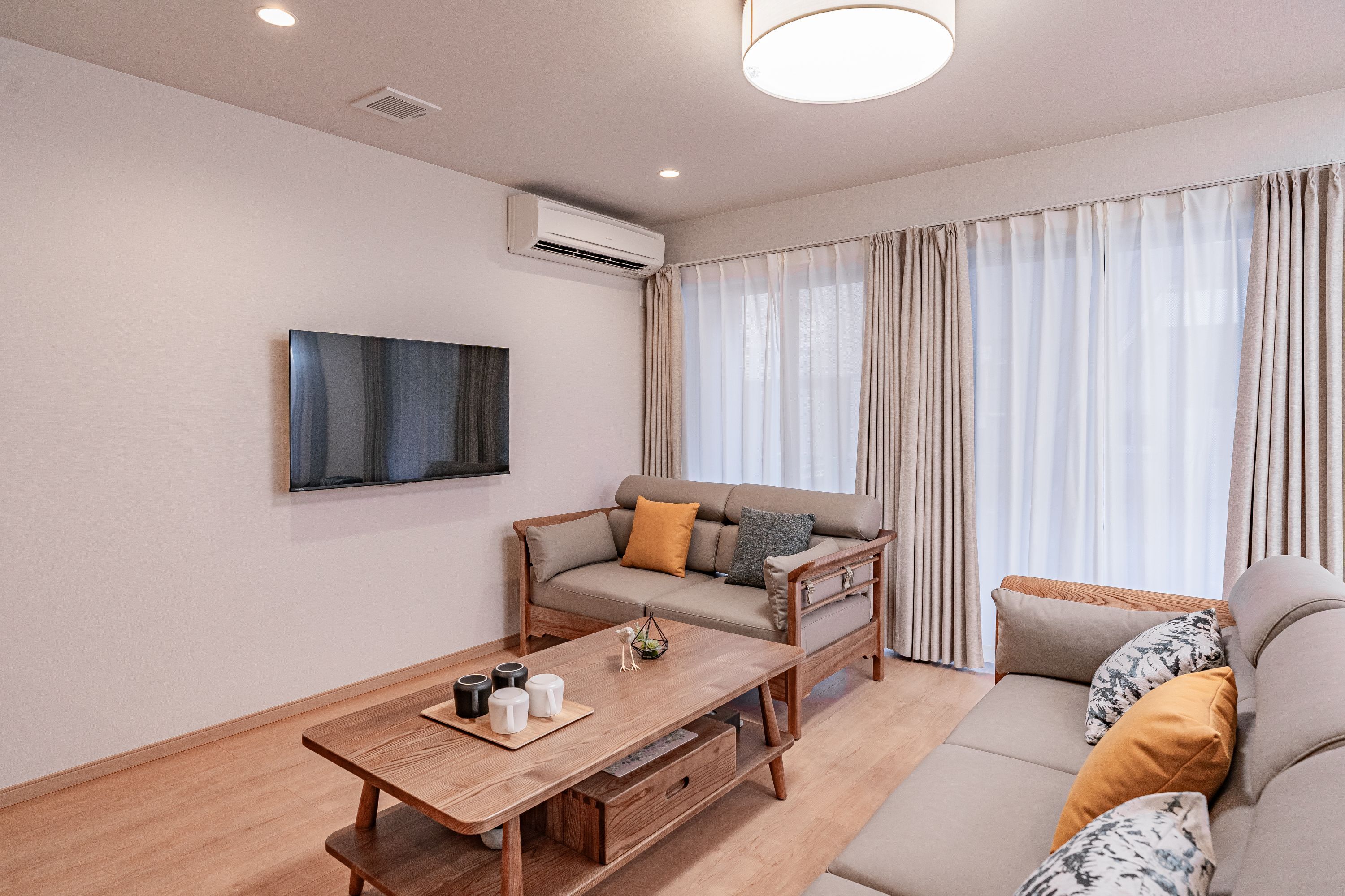 Uma sala de estar moderna com um sofá, uma mesa de centro e uma televisão de tela plana fixada na parede.
