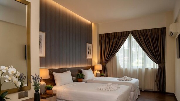 Quarto de hotel com duas camas, piso de madeira, um espelho grande e uma janela com cortinas.